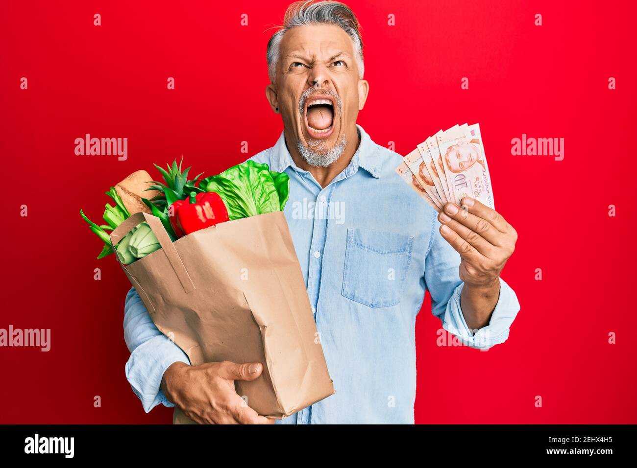 Middle age grey-haired man holding groceries and singapore dollars ...