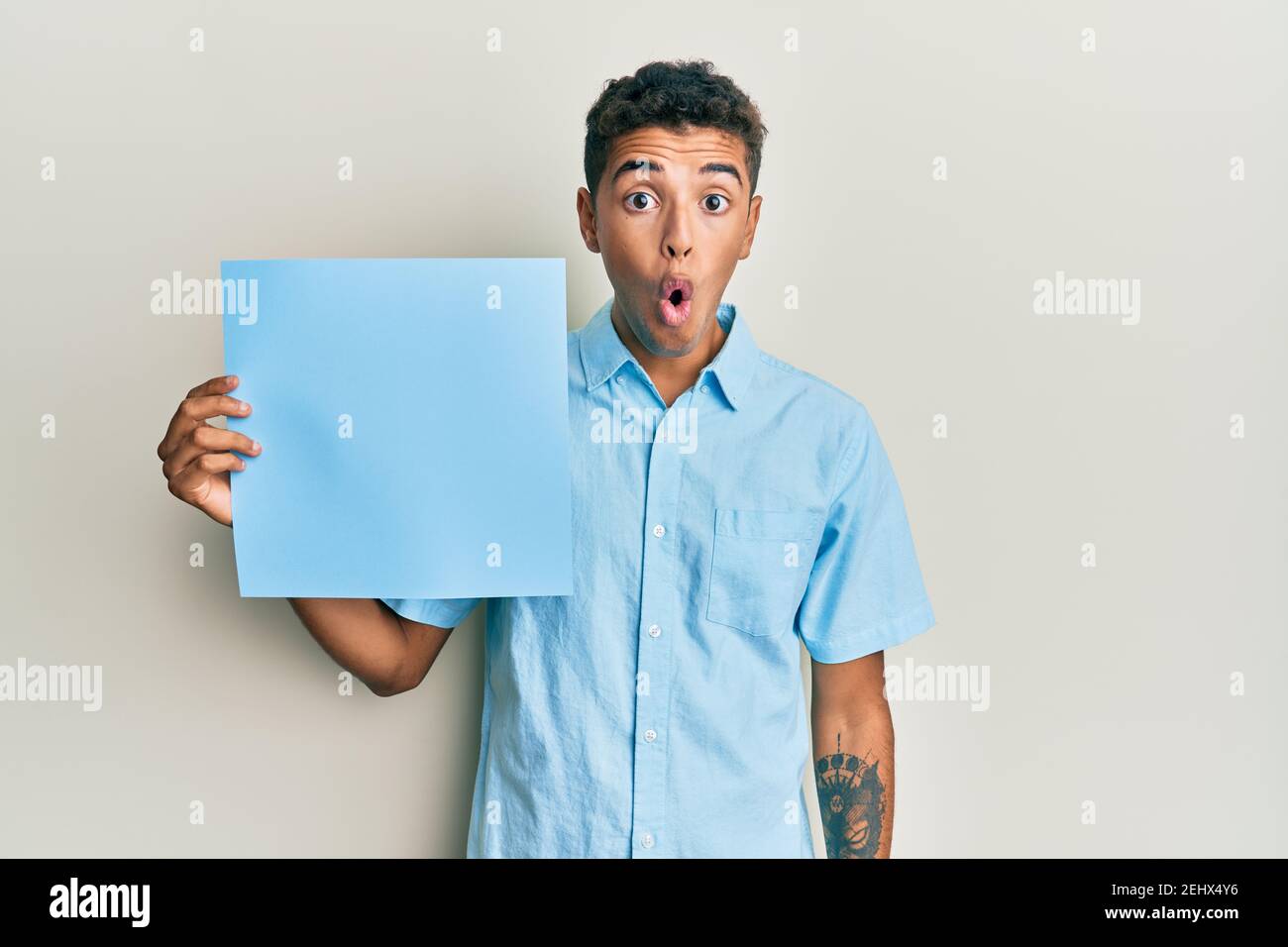 Young handsome african american man holding blue blank empty banner ...