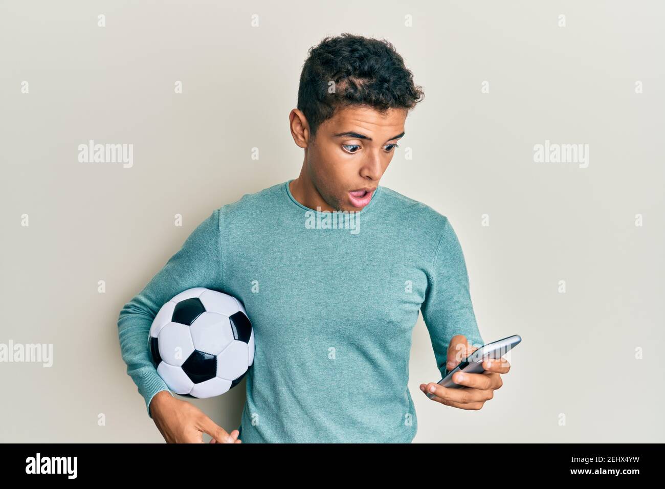 Young handsome african american man holding football ball looking at ...