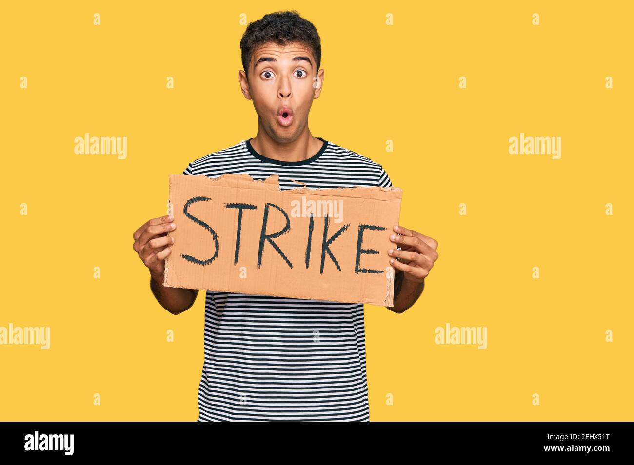 Young handsome african american man holding strike banner cardboard ...