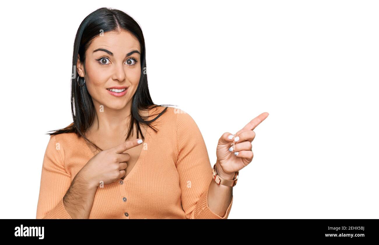 Young hispanic woman wearing casual clothes pointing aside worried and ...