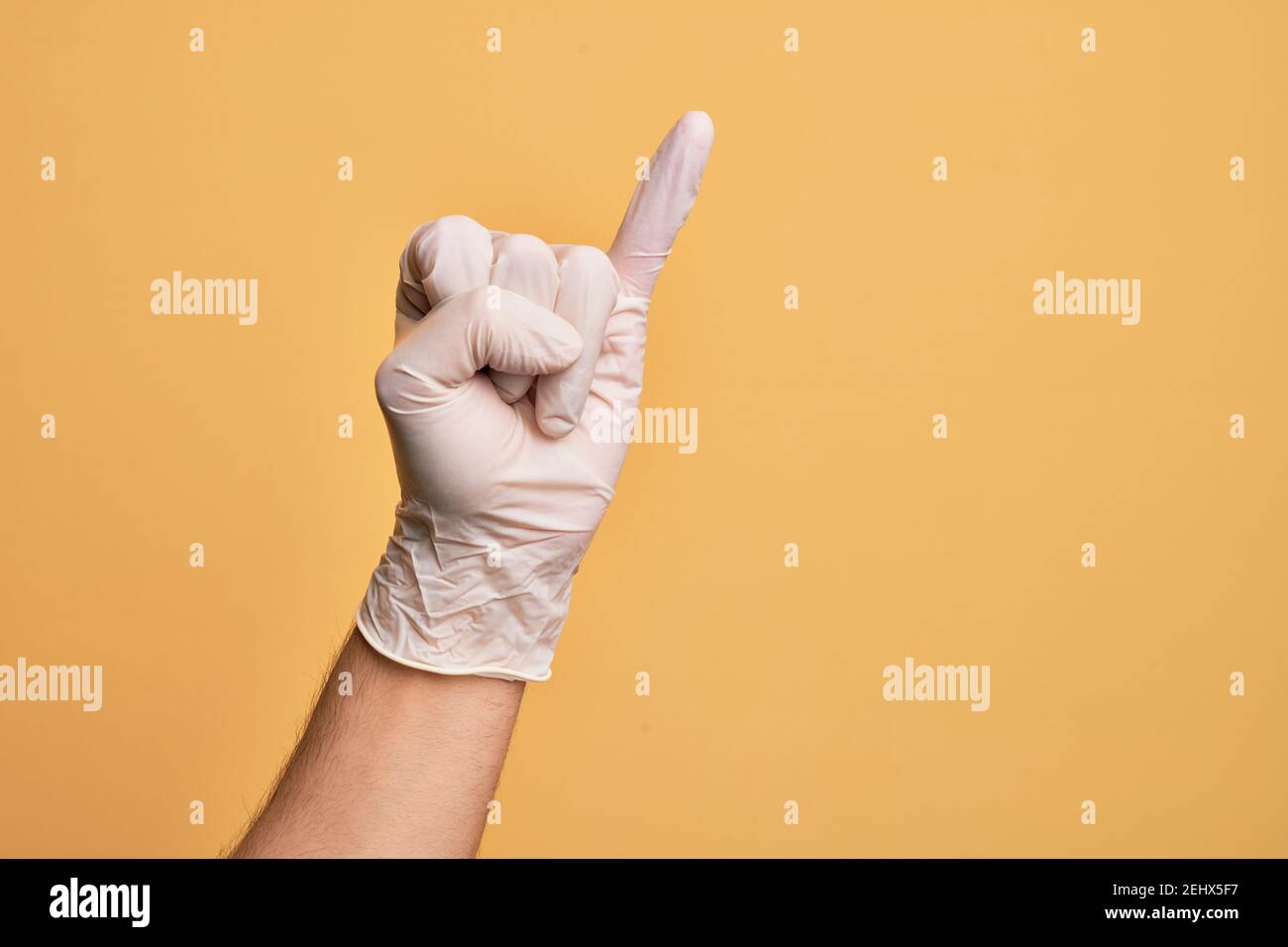 Hand of caucasian young man with medical glove over isolated yellow ...