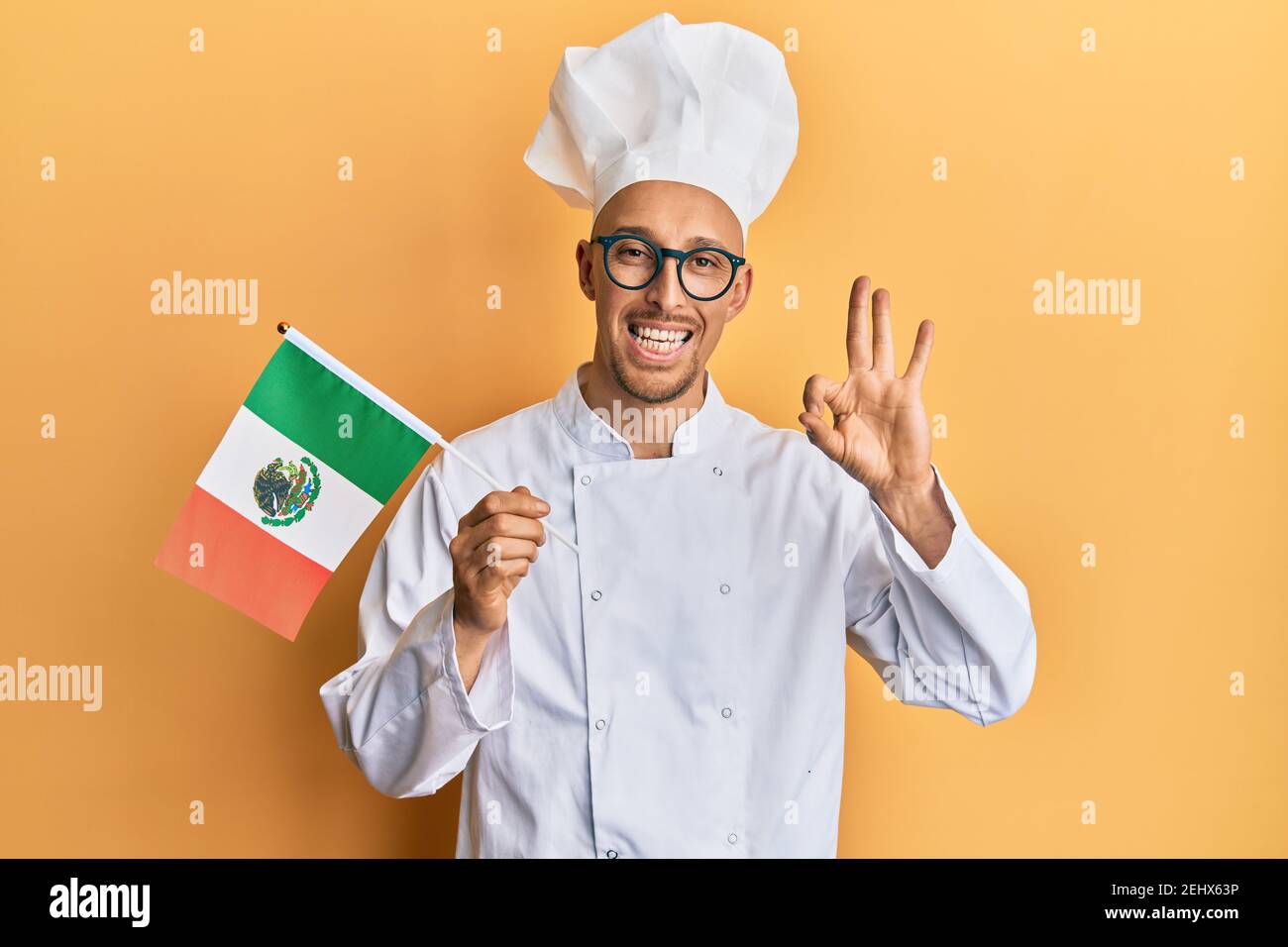 Bald man with beard wearing professional cook apron holding mexico flag ...