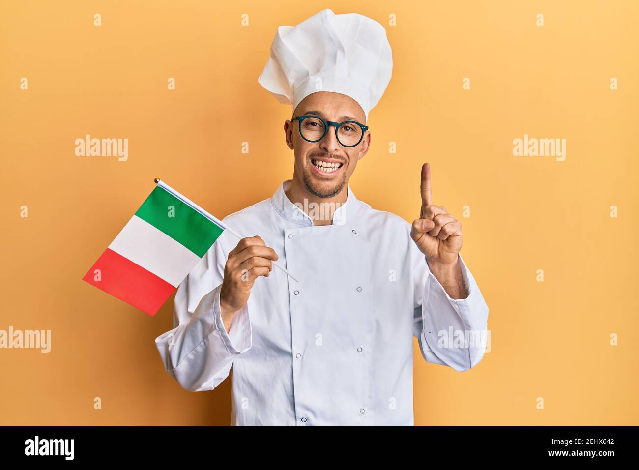 Bald man with beard wearing professional cook uniform holding italian ...