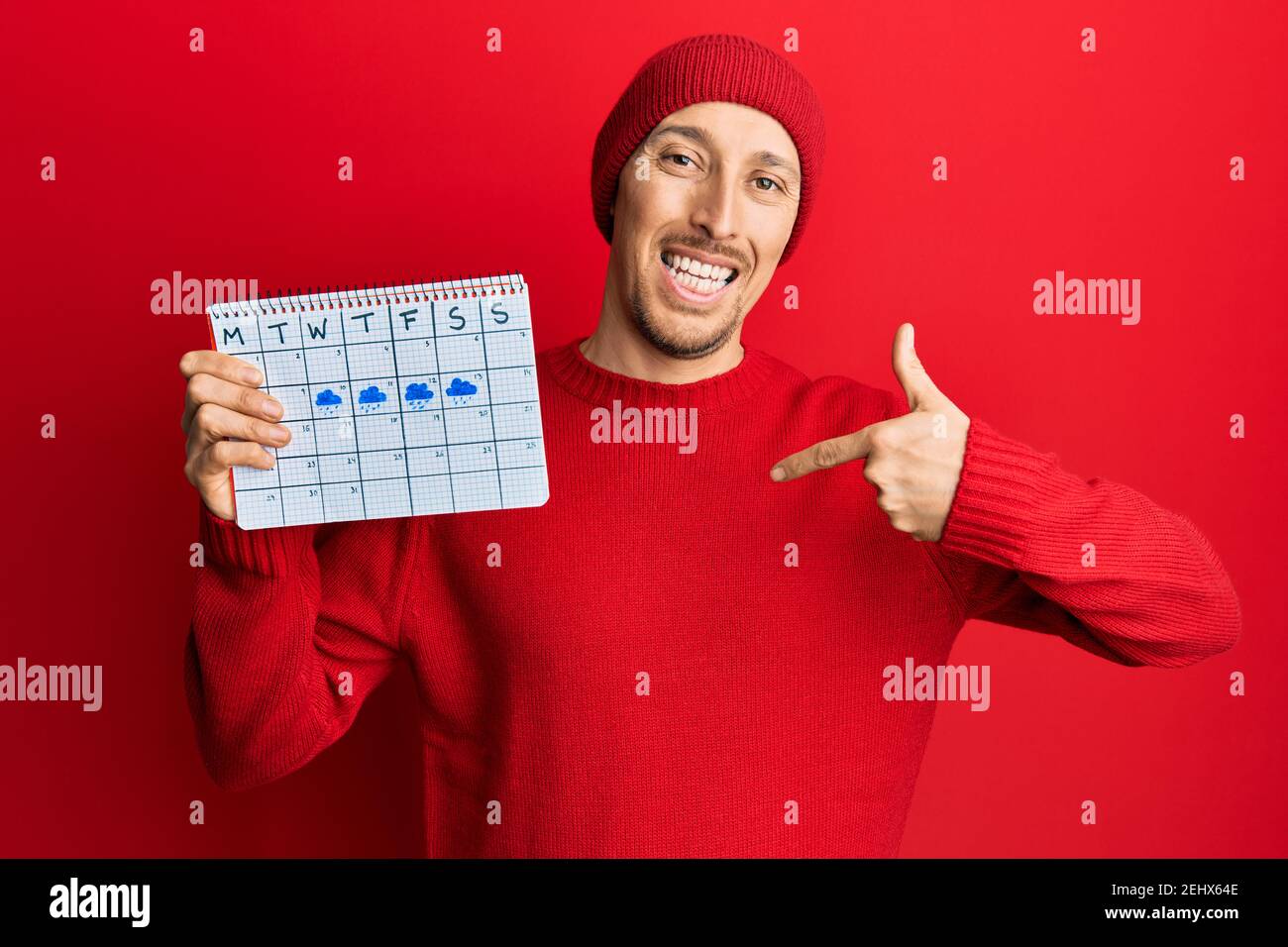 Bald man with beard holding rainy weather calendar pointing finger to ...
