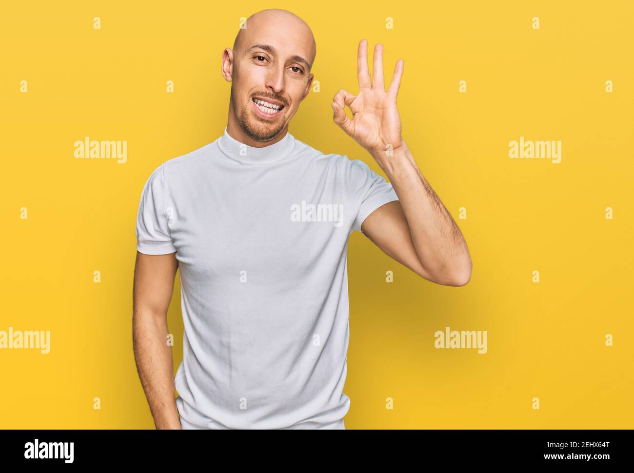 Bald man with beard wearing casual white t shirt smiling positive doing ...