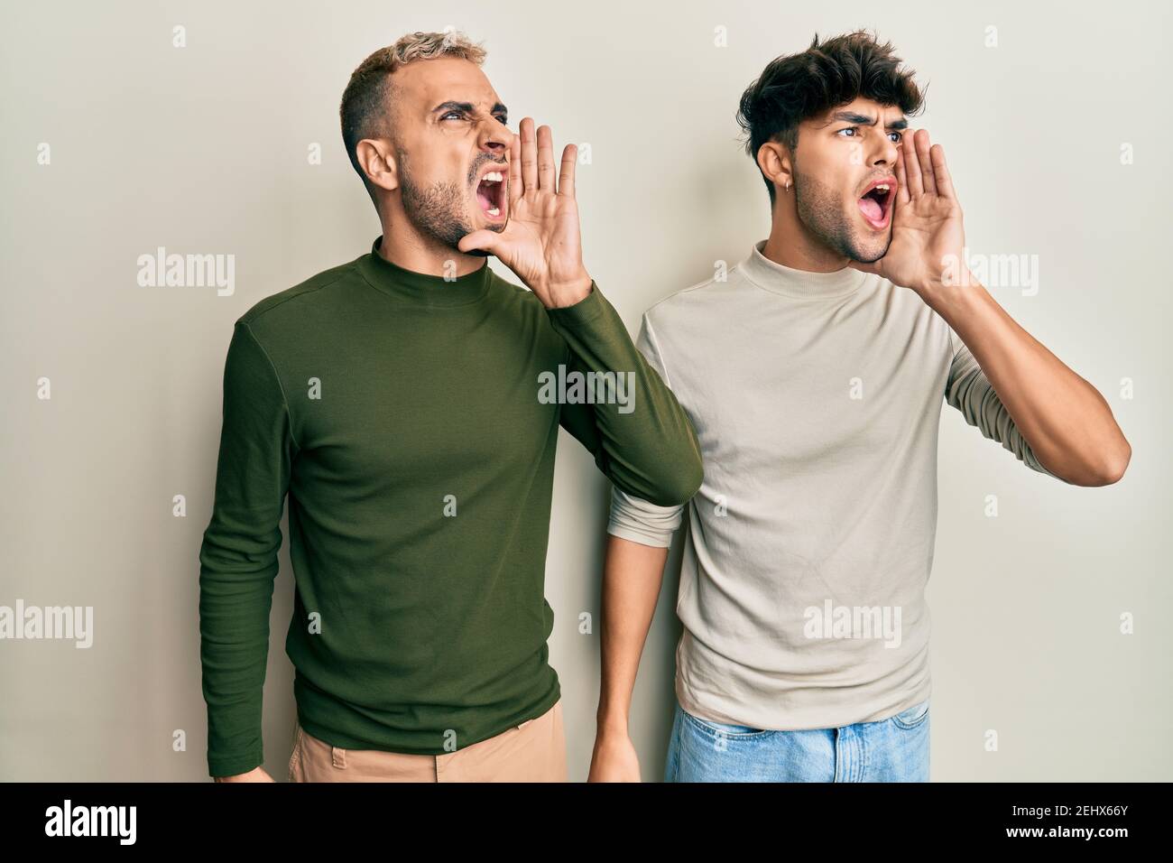 Homosexual gay couple standing together wearing casual clothes shouting ...
