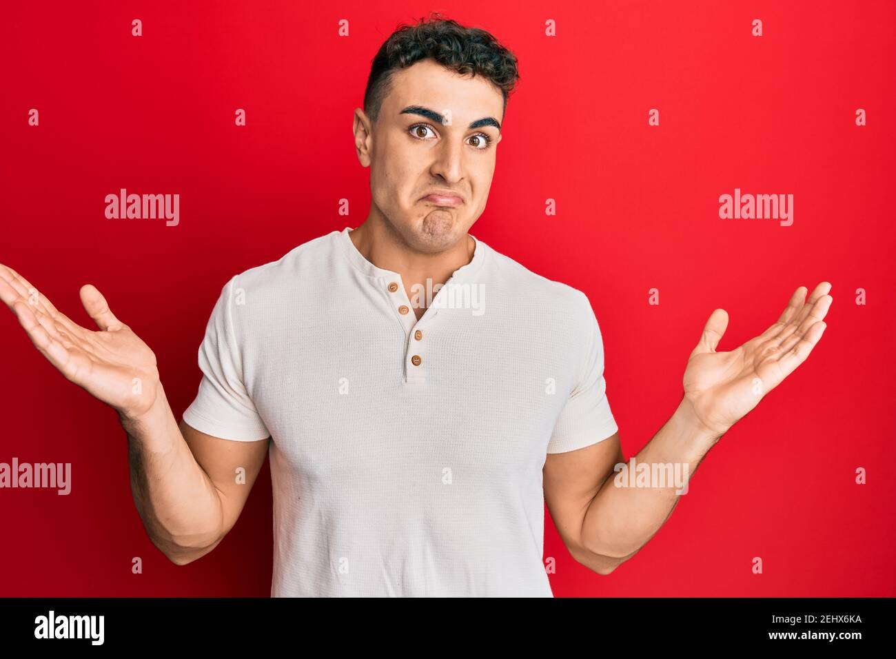Hispanic young man wearing casual white t shirt clueless and confused ...