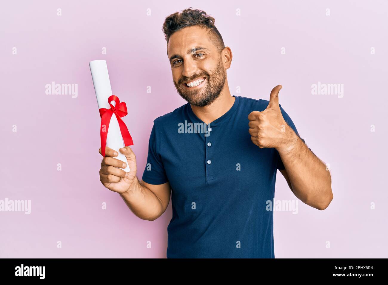 Handsome man with beard holding graduate degree diploma smiling happy ...