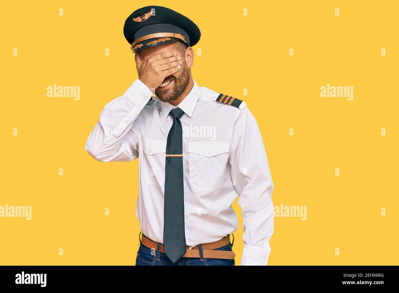 Handsome man with beard wearing airplane pilot uniform smiling and ...