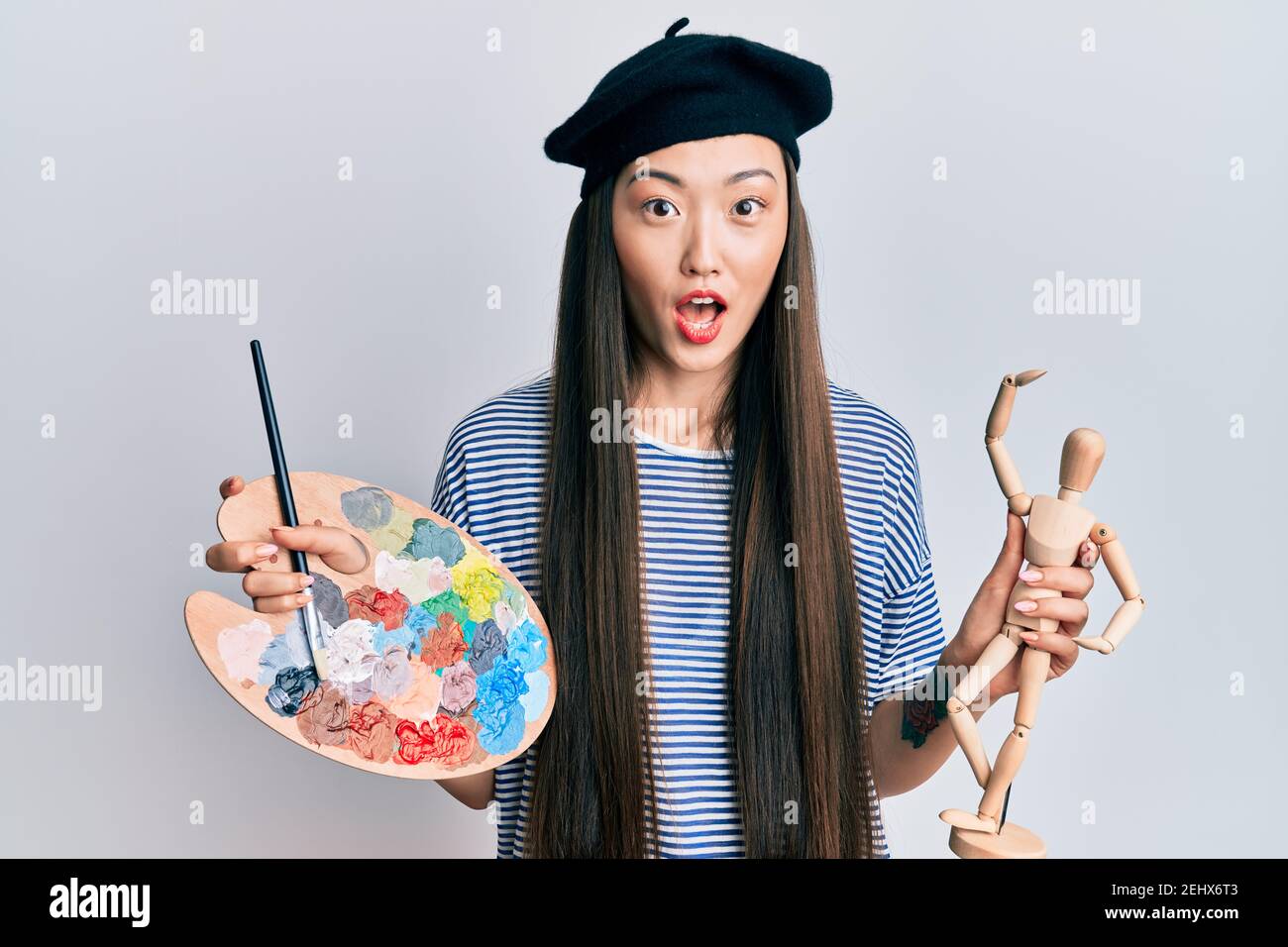 Young chinese woman wearing artist look with beret holding manikin ...