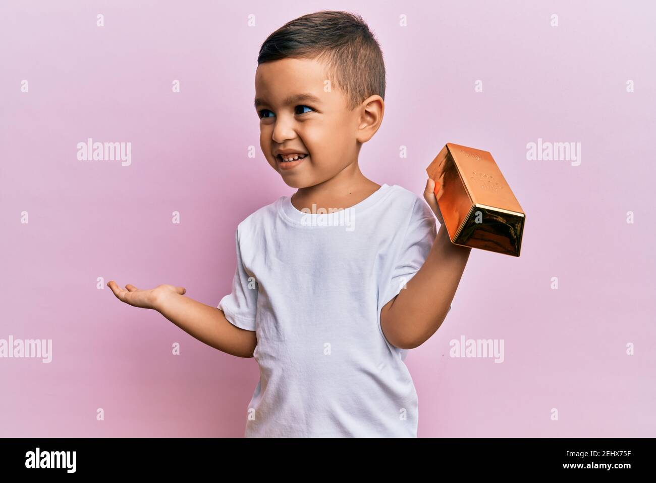Adorable latin toddler holding gold ingot celebrating achievement with ...