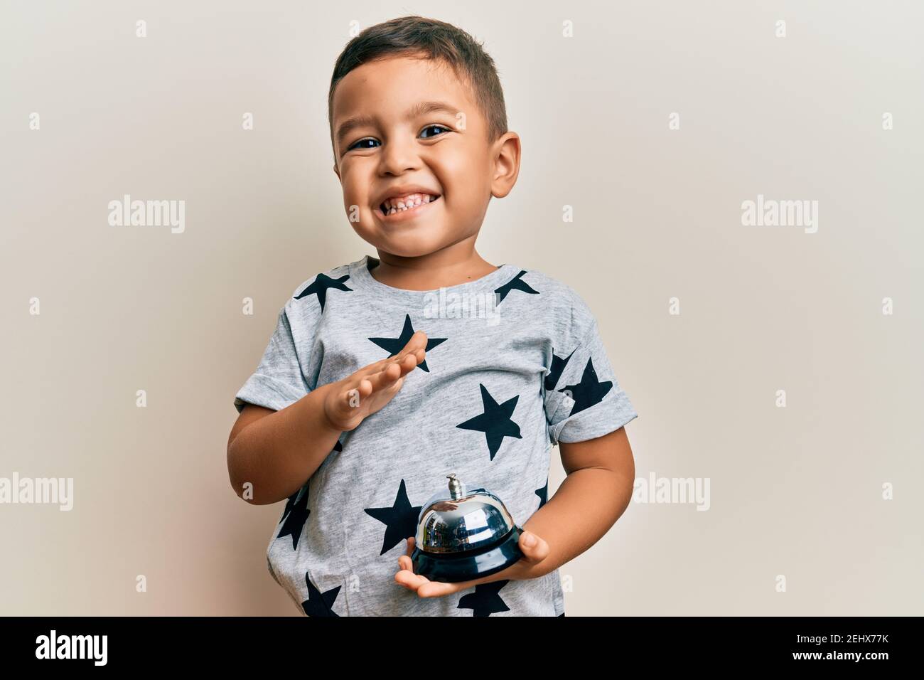 Adorable latin toddler smiling happy using receptionist ring bell over ...