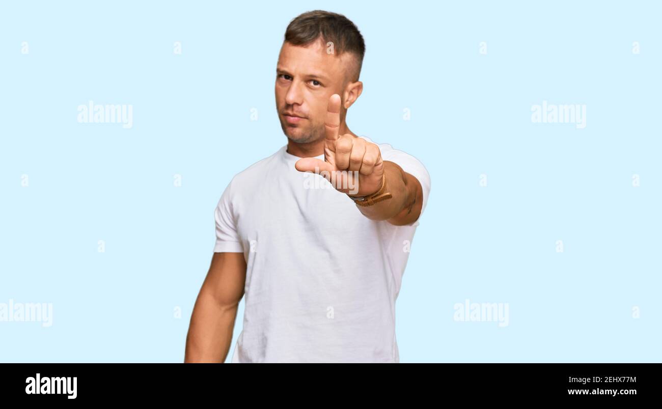 Handsome muscle man wearing casual white tshirt pointing with finger up ...