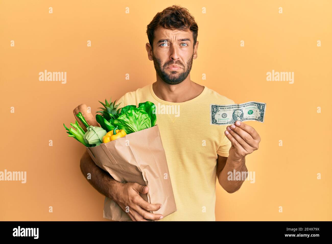 Handsome man with beard holding groceries and 1 american dollar ...