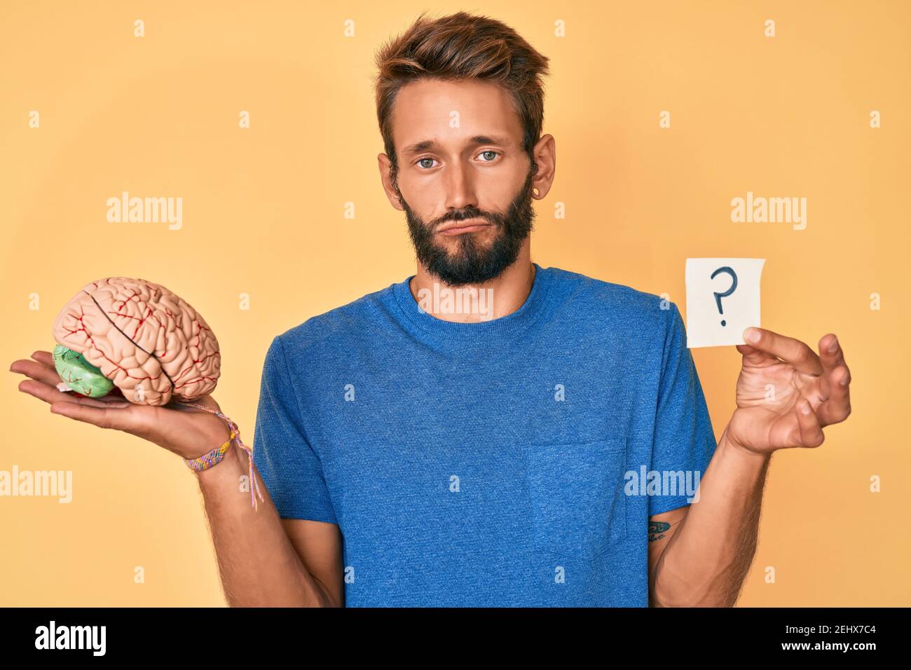 Handsome caucasian man with beard holding brain and question mark ...
