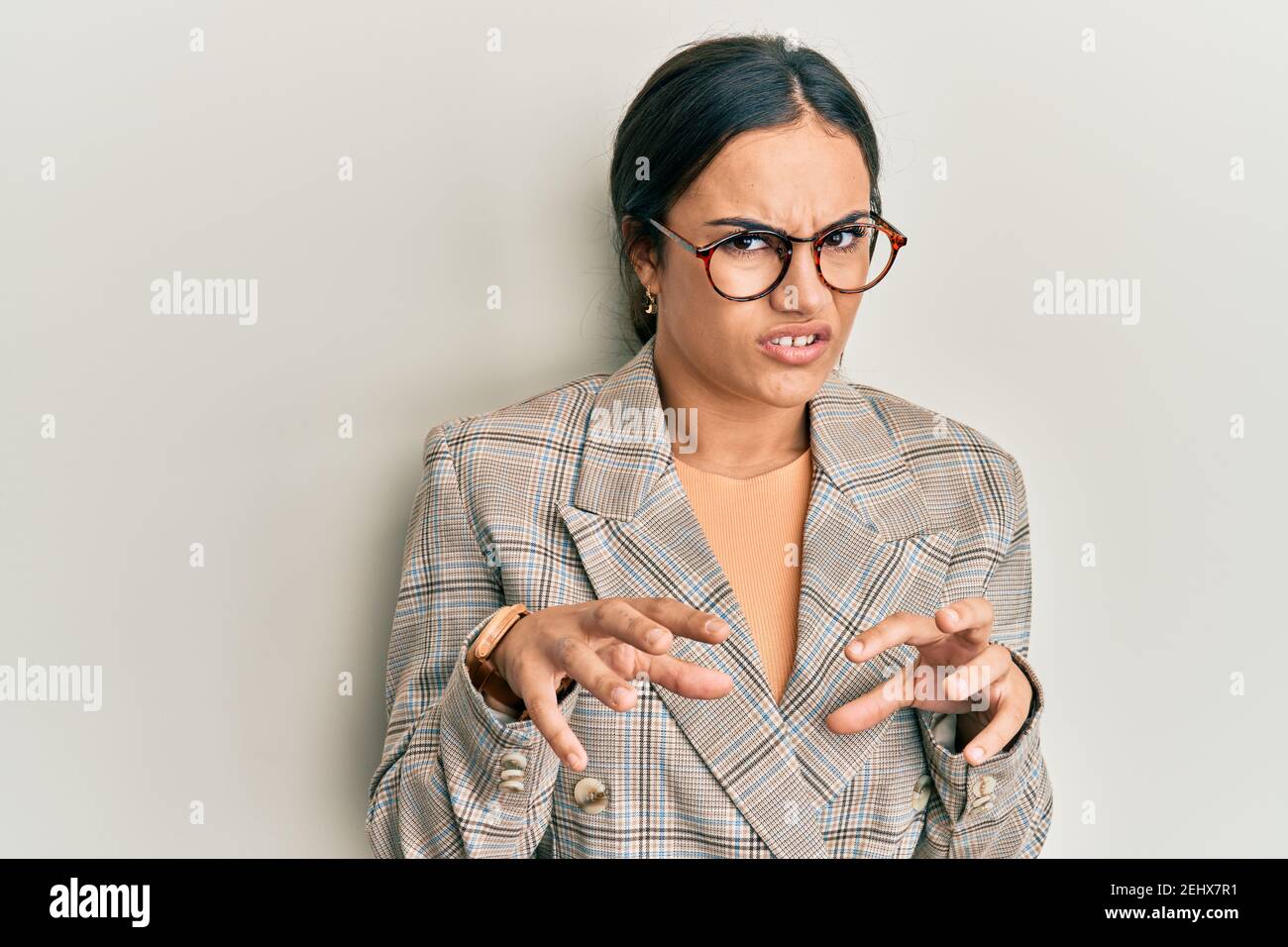 Young brunette woman wearing business jacket and glasses disgusted ...