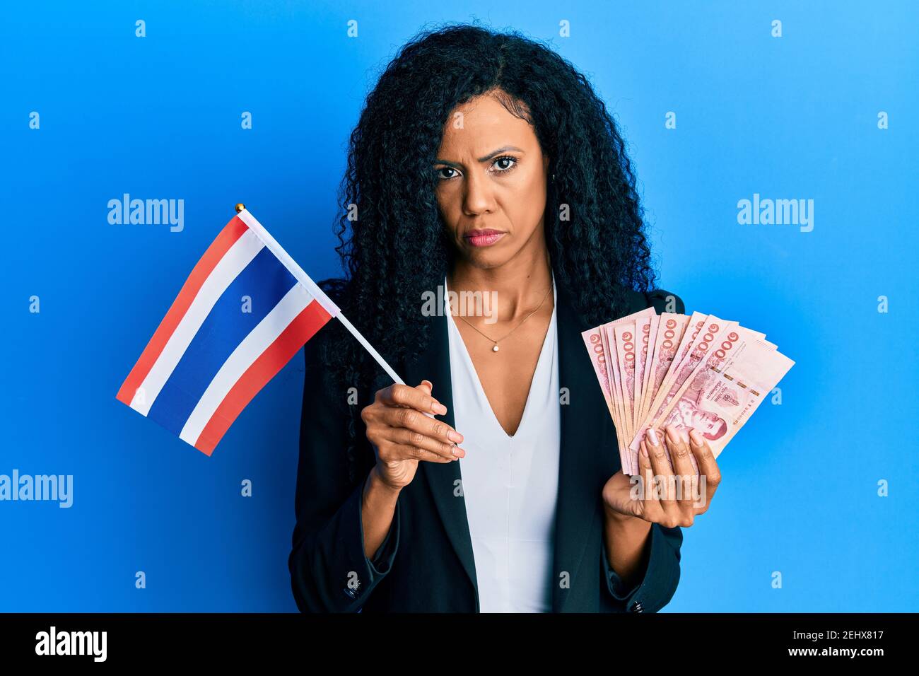 Middle age african american woman holding thailand flag and baht ...