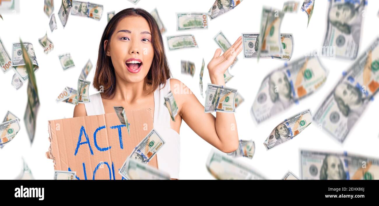 Young beautiful chinese girl holding act now banner celebrating victory ...