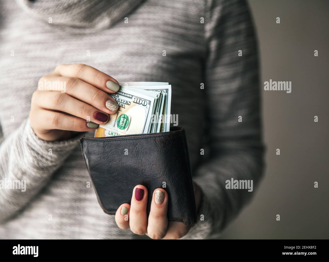 In the women's hands is the brown leather wallet with a wad of hundred ...