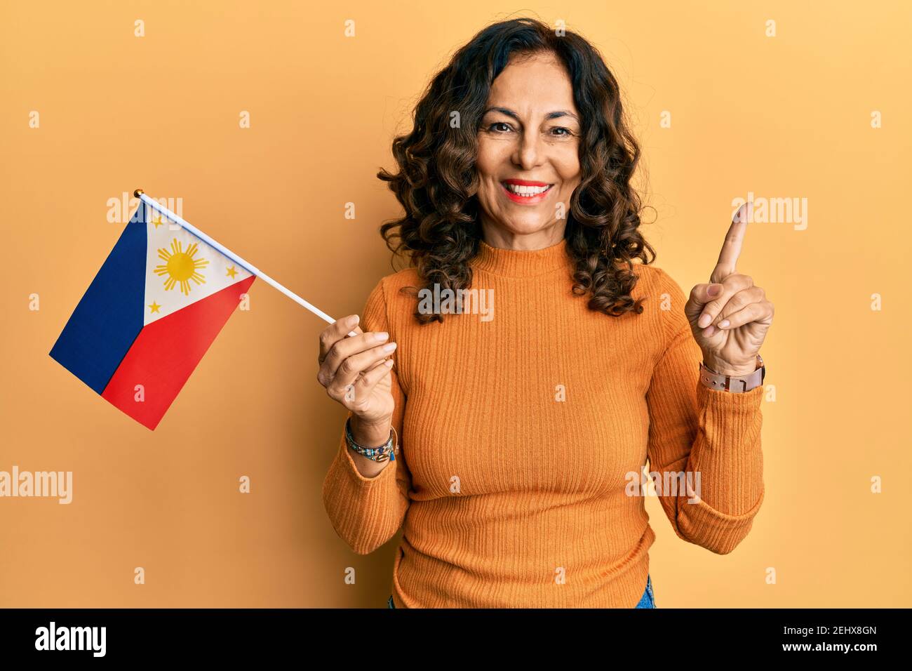 Middle age hispanic woman holding philippines flag smiling happy ...