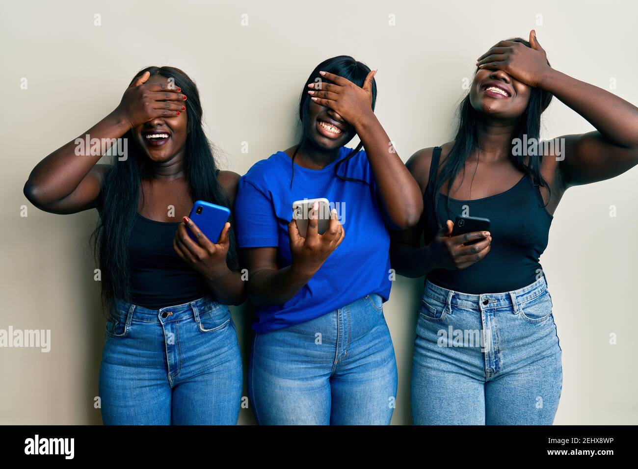 Three young african american friends using smartphone smiling and ...