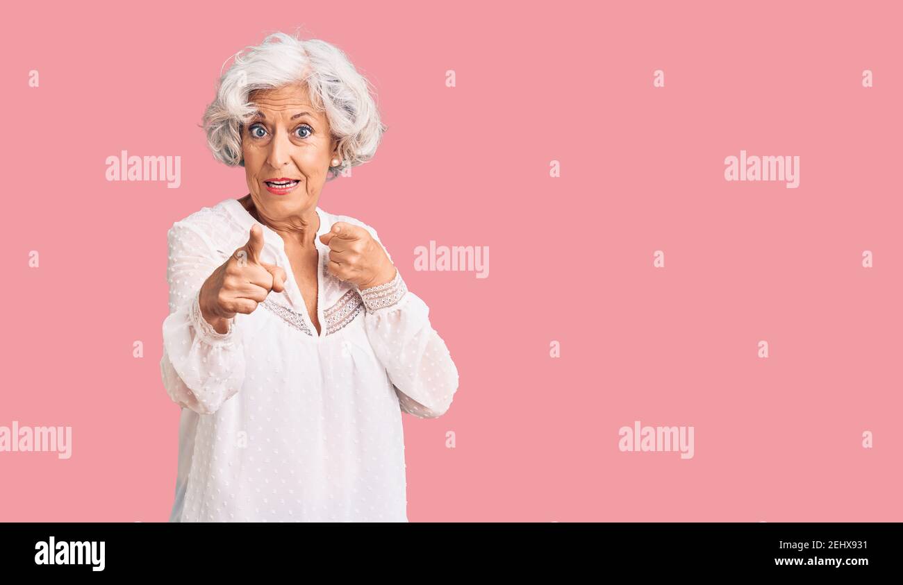 Senior grey-haired woman wearing casual clothes pointing fingers to ...