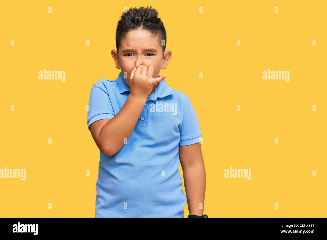 Little boy hispanic kid wearing casual clothes smelling something ...