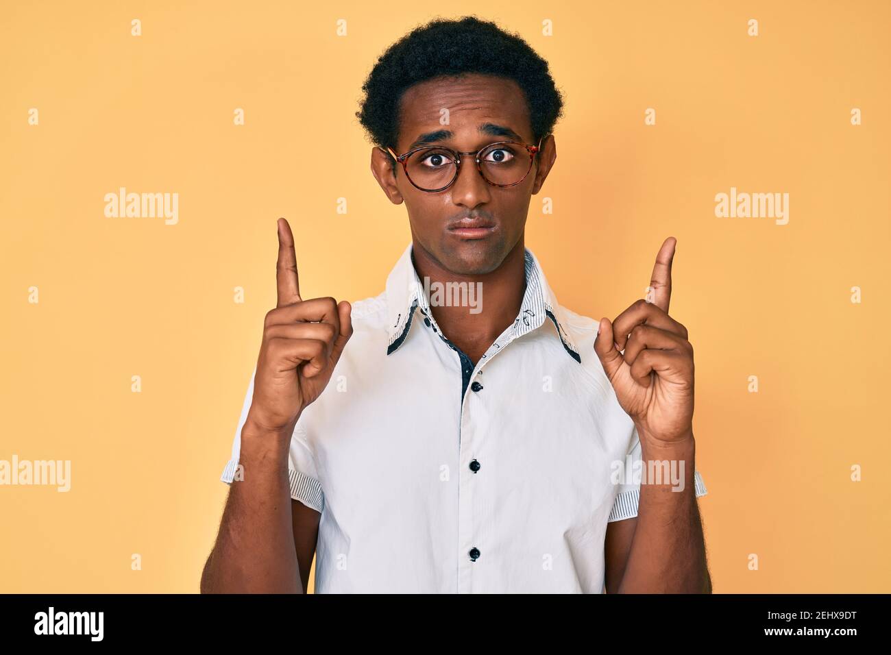 African handsome man pointing up with fingers depressed and worry for ...