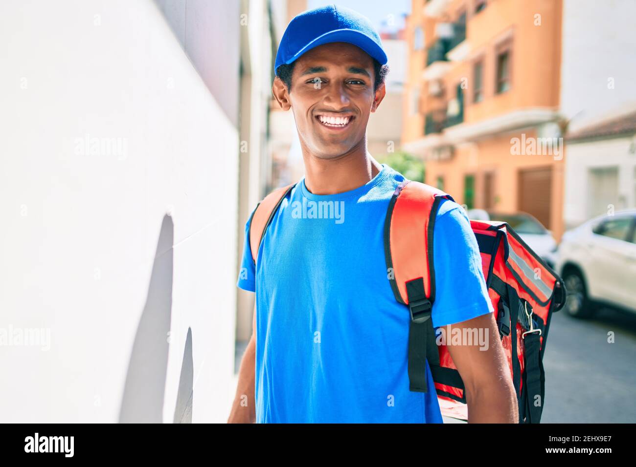 African delivery man wearing courier uniform and backpack outdoors ...