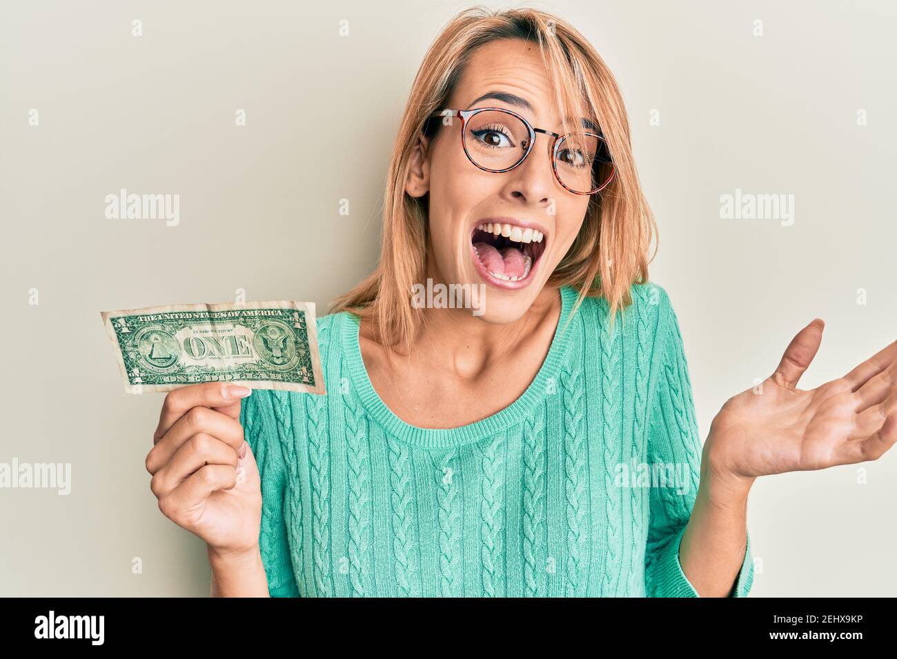 Beautiful blonde woman holding 1 dollar banknote celebrating ...