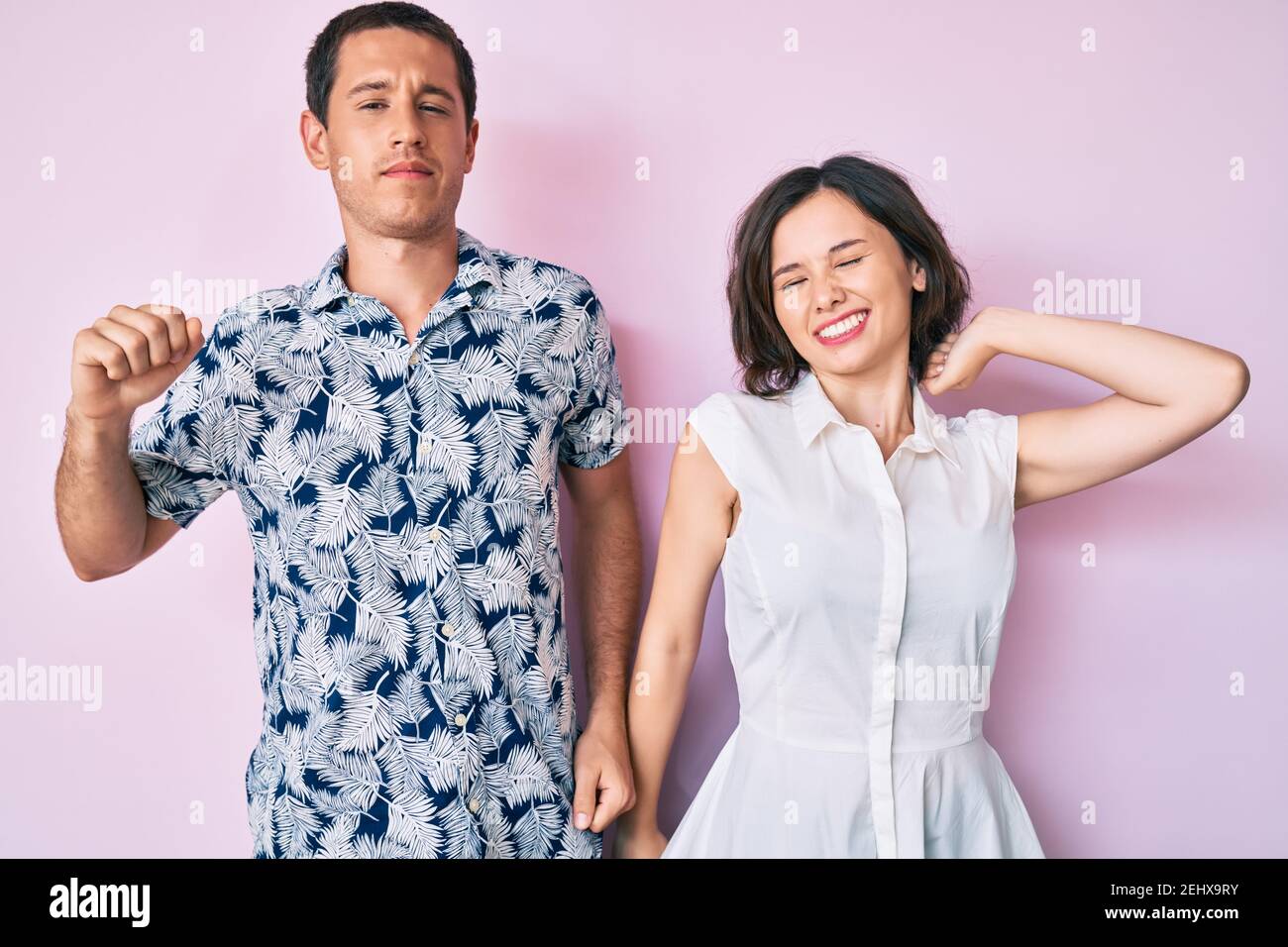 Beautiful couple wearing casual clothes stretching back, tired and ...