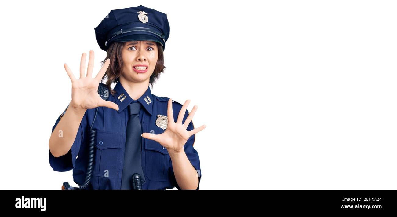 Young beautiful girl wearing police uniform afraid and terrified with ...