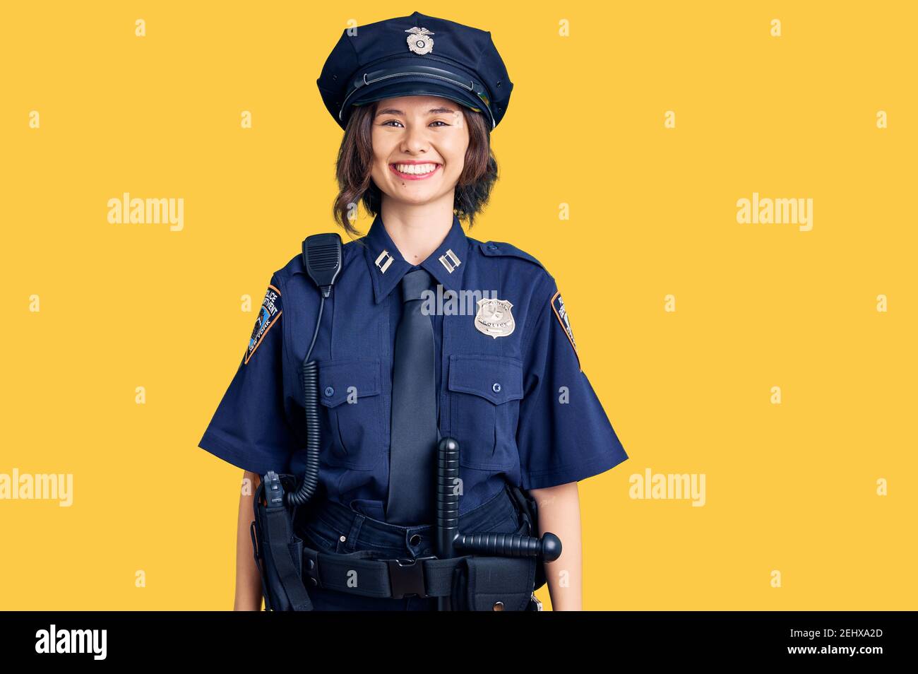 Young beautiful girl wearing police uniform with a happy and cool smile ...