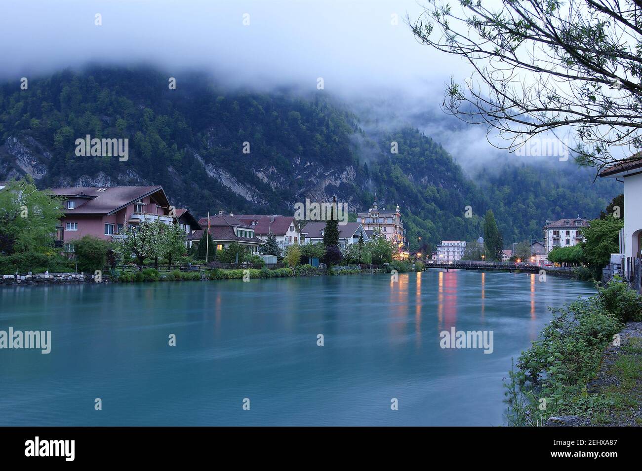 Switzerland, Interlaken. Evening view of a small river in the downtown ...