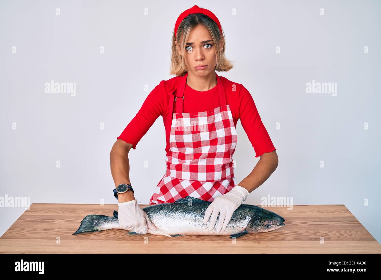 Beautiful caucasian woman fishmonger selling fresh raw salmon depressed ...