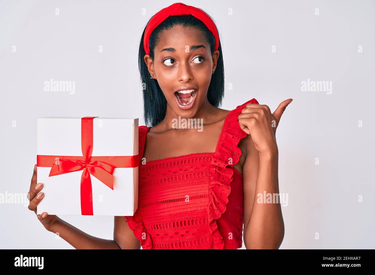Young African American Woman Holding T Pointing Thumb Up To The Side