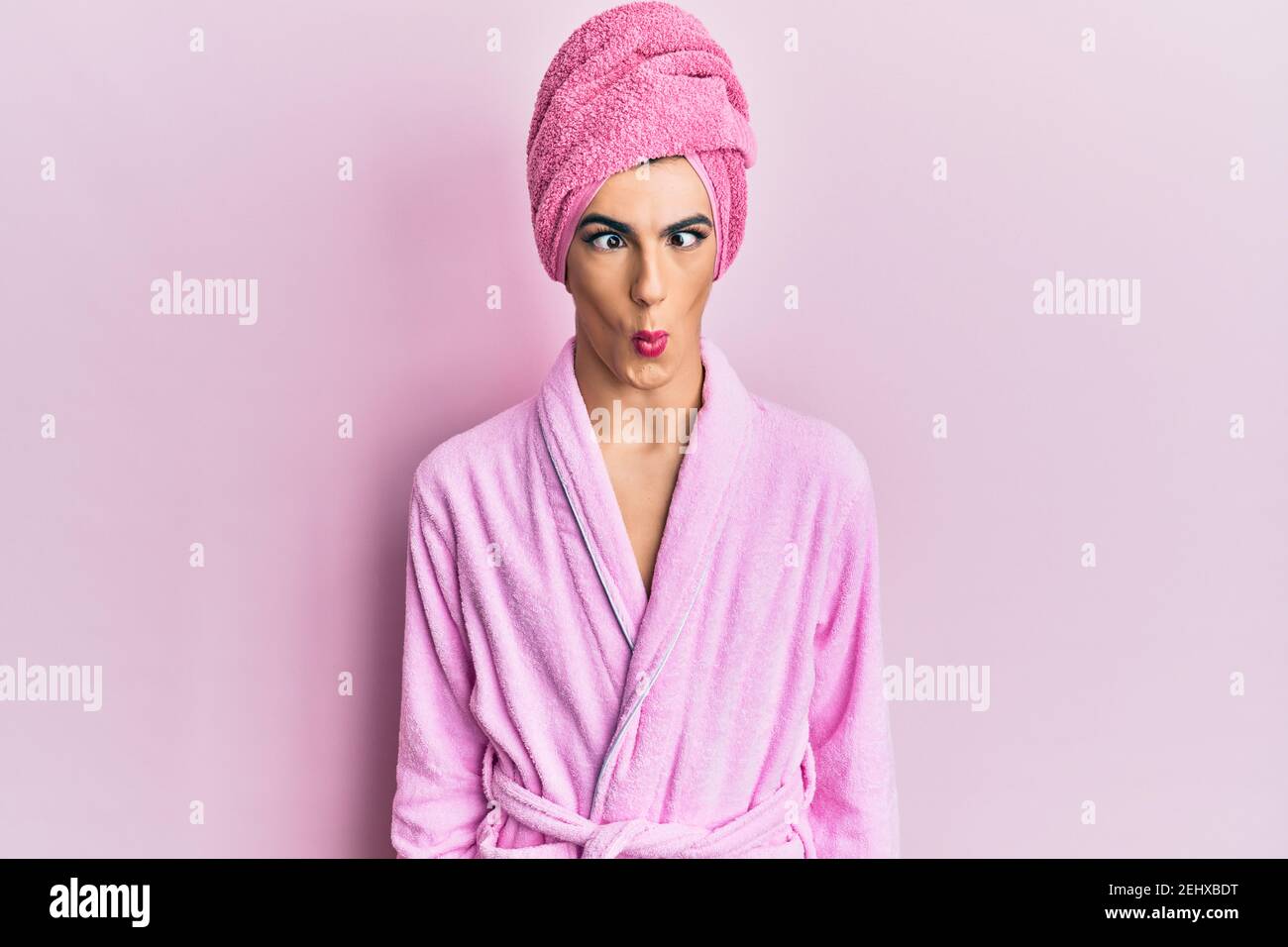 Young man wearing woman make up wearing shower towel on head and ...
