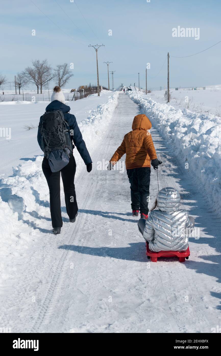 family enjoying a sleigh ride in the snow with red sled Stock Photo - Alamy