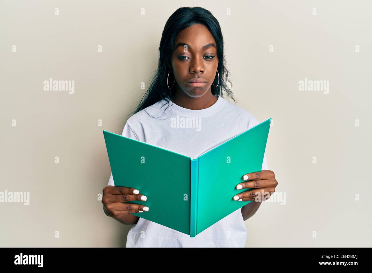 Young african american woman reading book depressed and worry for ...
