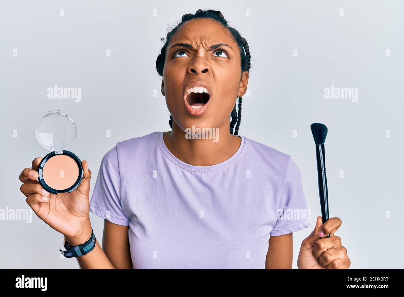 African american woman holding makeup brush and blush angry and mad ...