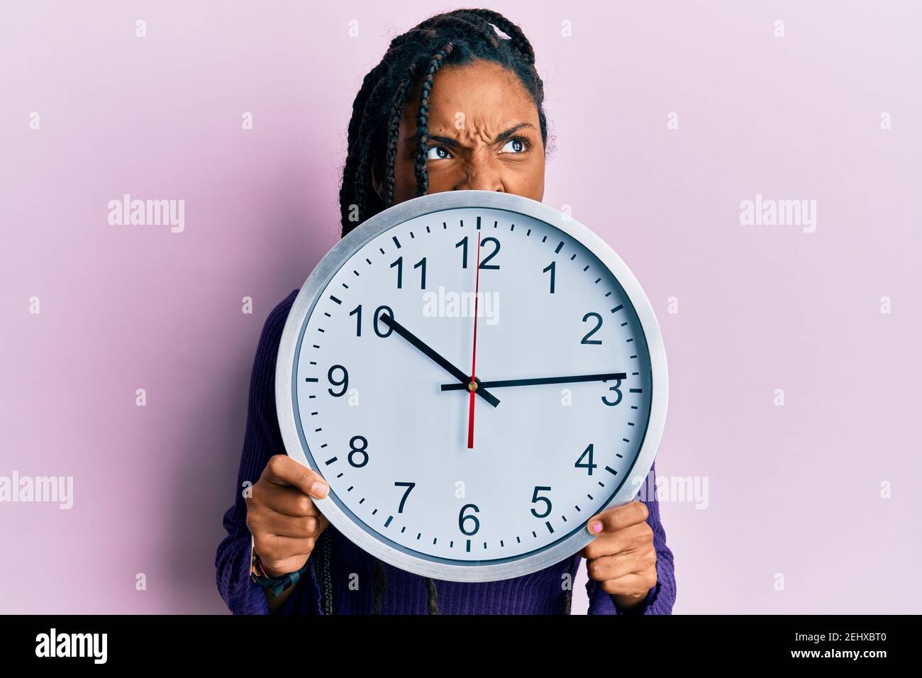 African american woman with braids holding big clock covering face ...