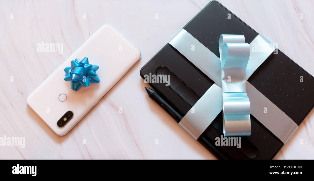 digital tablet with mobile wrapped with blue ribbons Stock Photo - Alamy