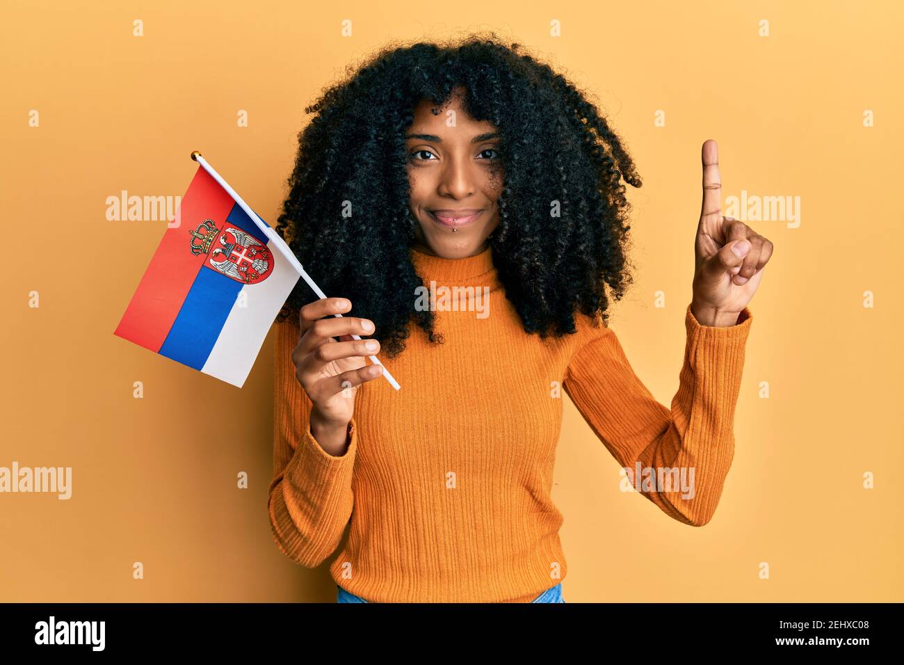 African american woman with afro hair holding serbia flag smiling with ...