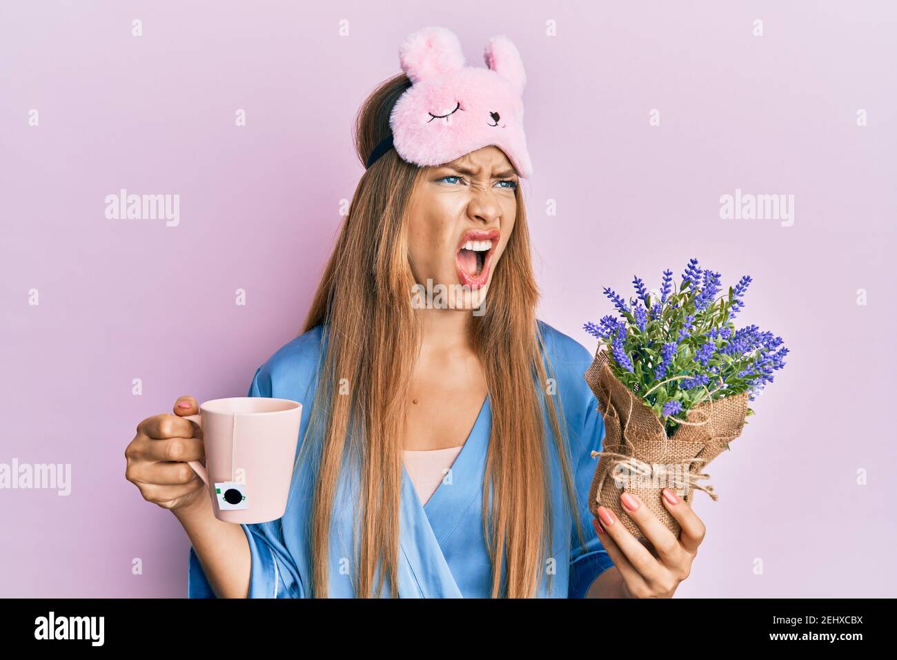 Beautiful young blonde woman wearing pajama drinking a cup of infused ...