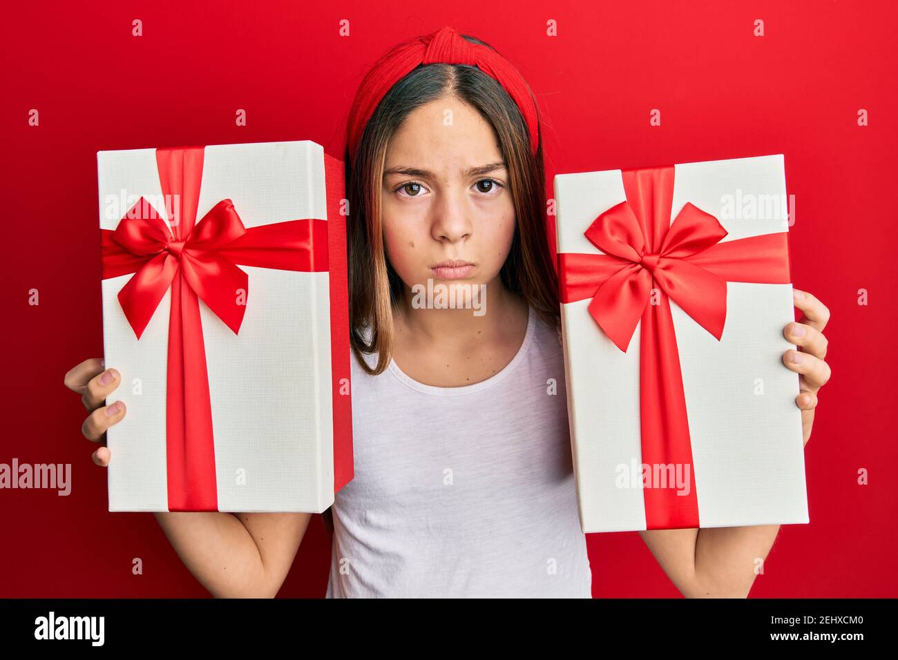 Beautiful brunette little girl holding gifts depressed and worry for ...