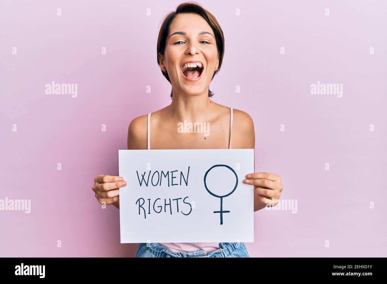 Young brunette woman with short hair holding woman rights banner ...