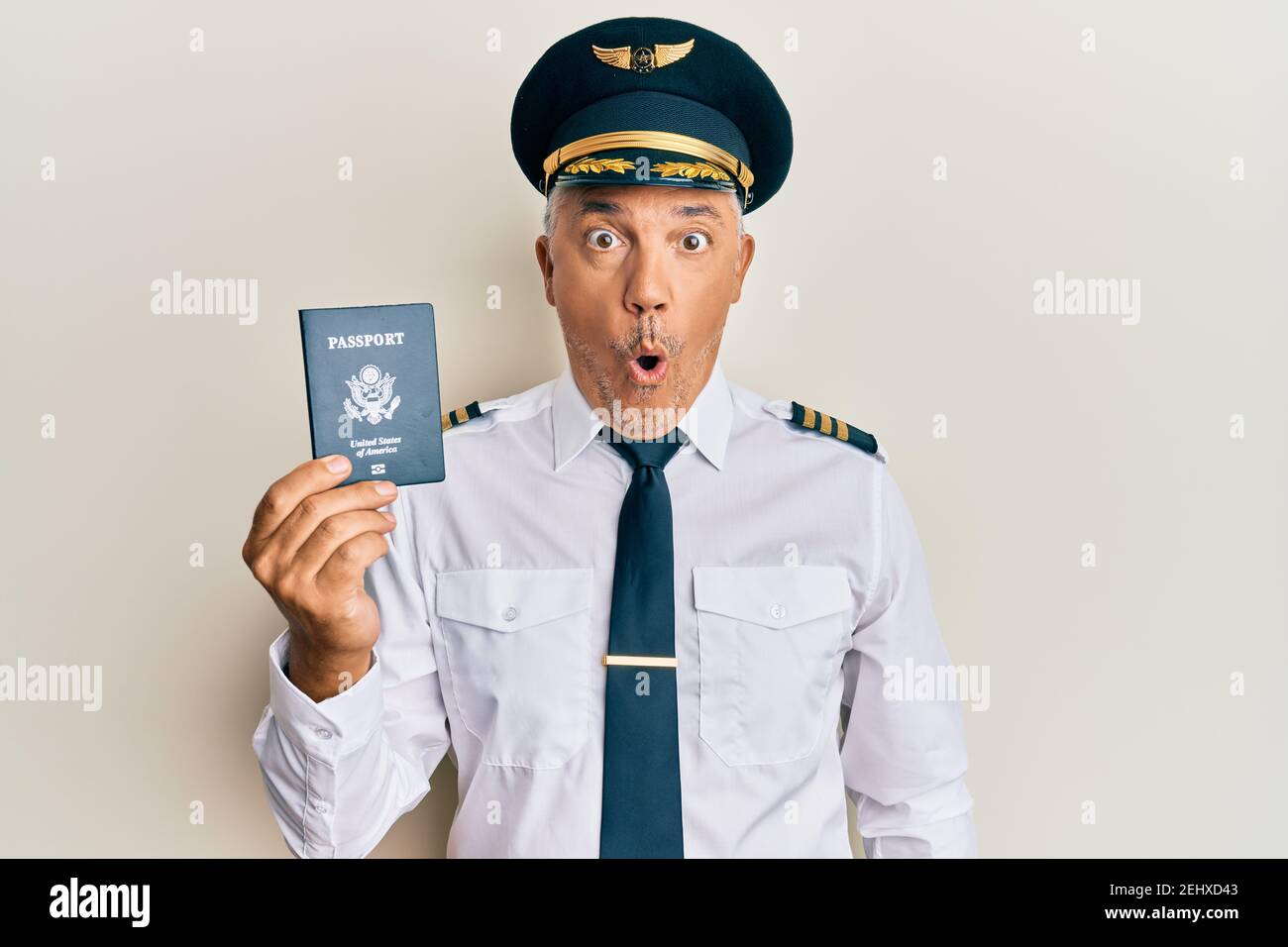 Handsome middle age mature pilot man holding usa passport scared and ...