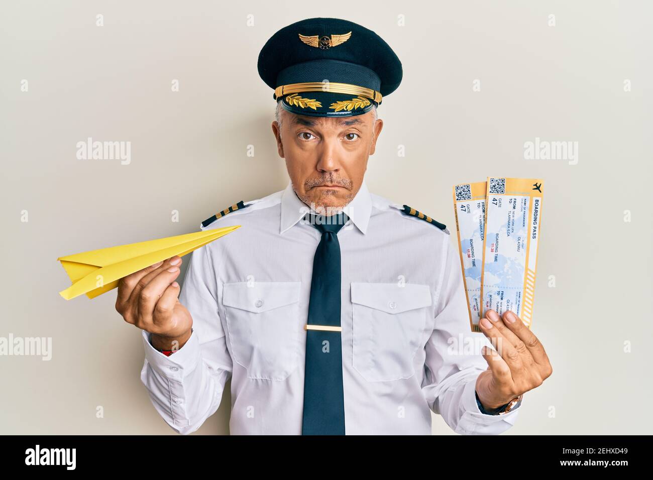 Handsome middle age mature pilot man holding paper plane and boarding ...