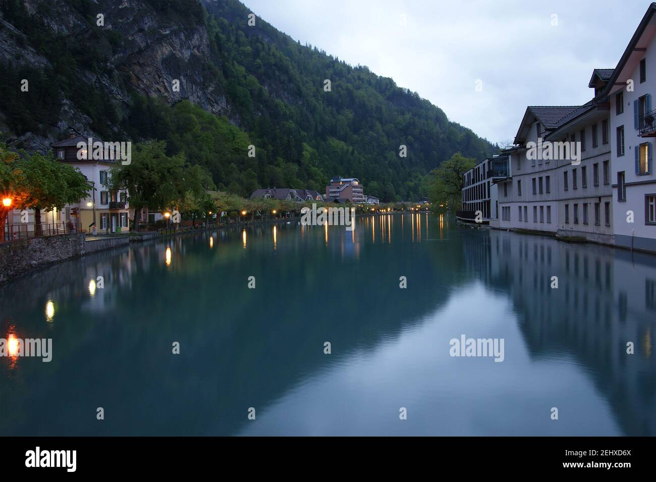 Switzerland, Interlaken. Evening view of a small river in the downtown ...